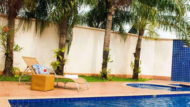Piscina com espreguiçadeiras e palmeiras.