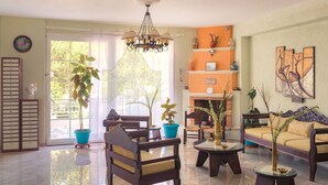 Uma sala de estar ampla com lustre, móveis de madeira e plantas em vasos.