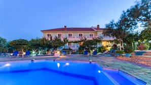 Piscina com espreguiçadeiras e um edifício ao fundo.