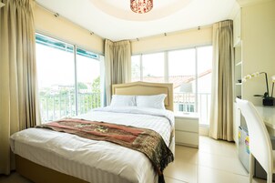 Quarto de hotel com uma cama grande, uma escrivaninha e vista para o exterior.