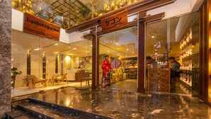 Um saguão de hotel com balcão de recepção, área de estar e entrada de vidro.