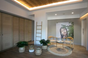 Quarto moderno com piso de madeira, uma mesa redonda com cadeiras e plantas em vasos.