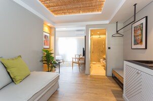 Uma sala de estar moderna com um sofá, uma planta e um espaço de jantar com cadeiras.