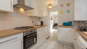 Uma cozinha moderna com armários brancos, fogão a gás, forno, micro-ondas e máquina de lavar.