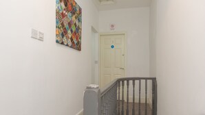 Um corredor com escada, uma obra de arte colorida na parede e uma porta identificada com o número 3.