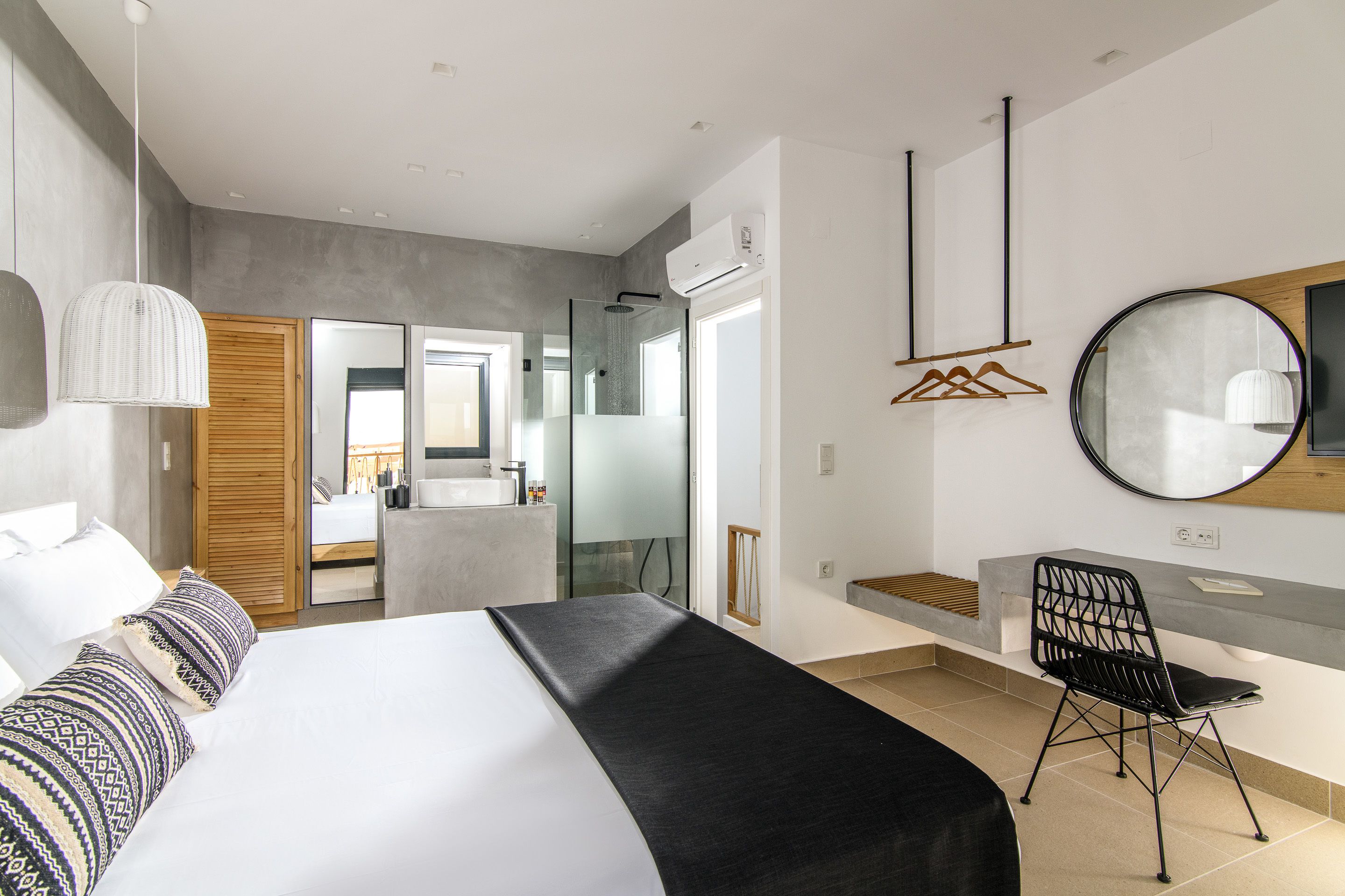 Quarto de hotel moderno com uma cama grande, uma escrivaninha, uma cadeira, um espelho e um lustre.