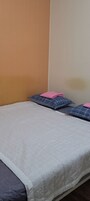 Uma cama com colcha cinza e dois travesseiros com padrão azul e rosa.