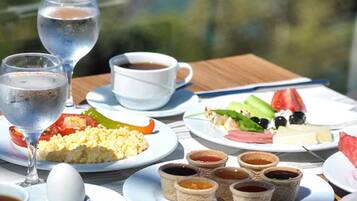 Mesa posta com itens de café da manhã, incluindo ovos mexidos, torradas e diversas geleias em pequenos recipientes.