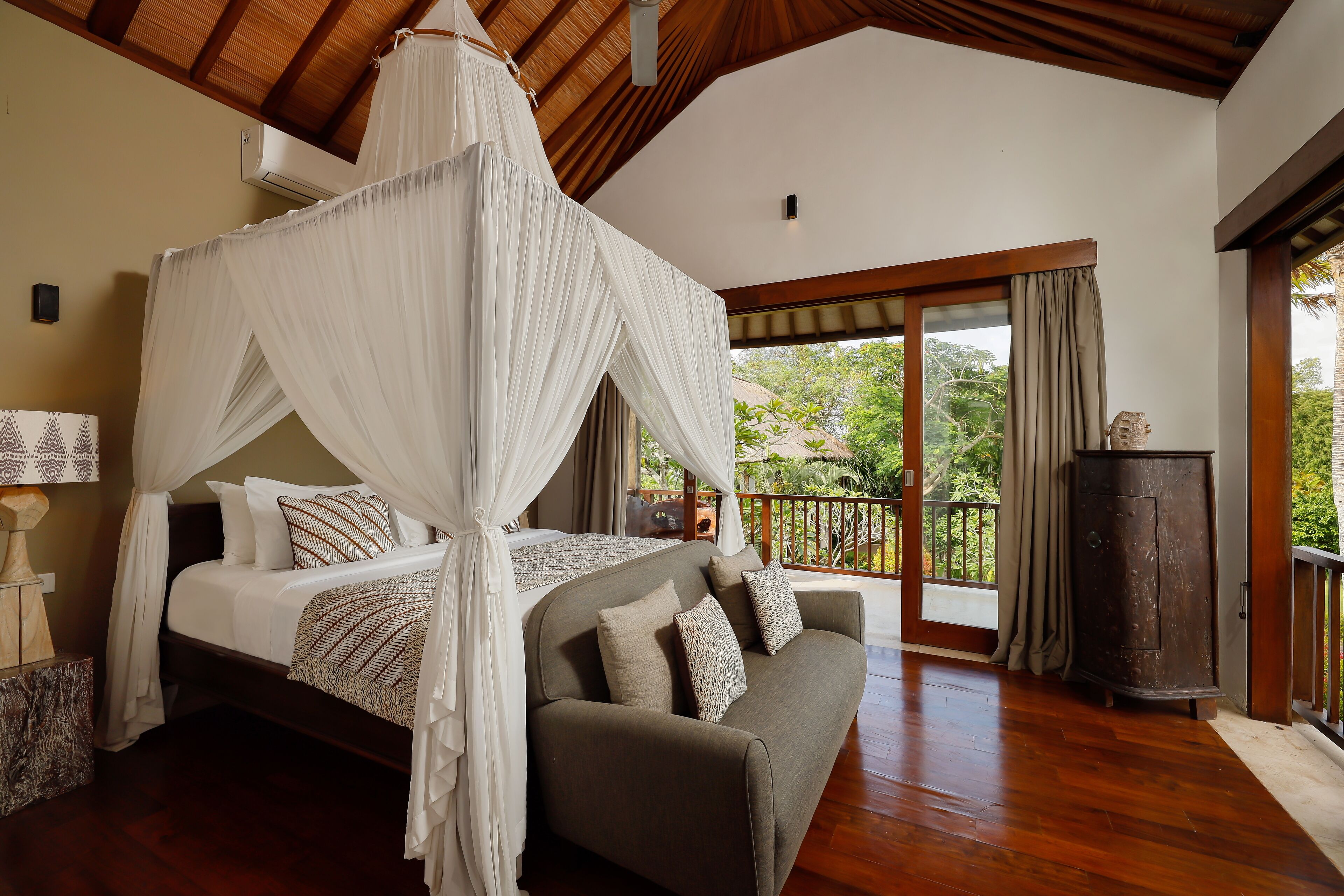 Quarto com cama de dossel, um sofá e vista para o exterior.