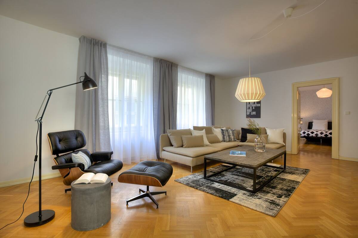 Uma sala de estar moderna com sofá, poltrona, banqueta e mesa de centro.