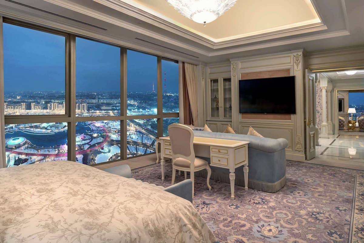 Um quarto de hotel luxuoso com uma cama grande, uma escrivaninha e uma televisão.