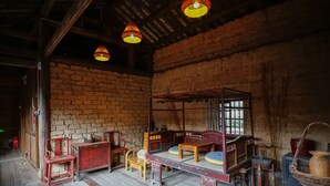 Um quarto rústico com cama de madeira, cadeiras vermelhas e parede de tijolos.