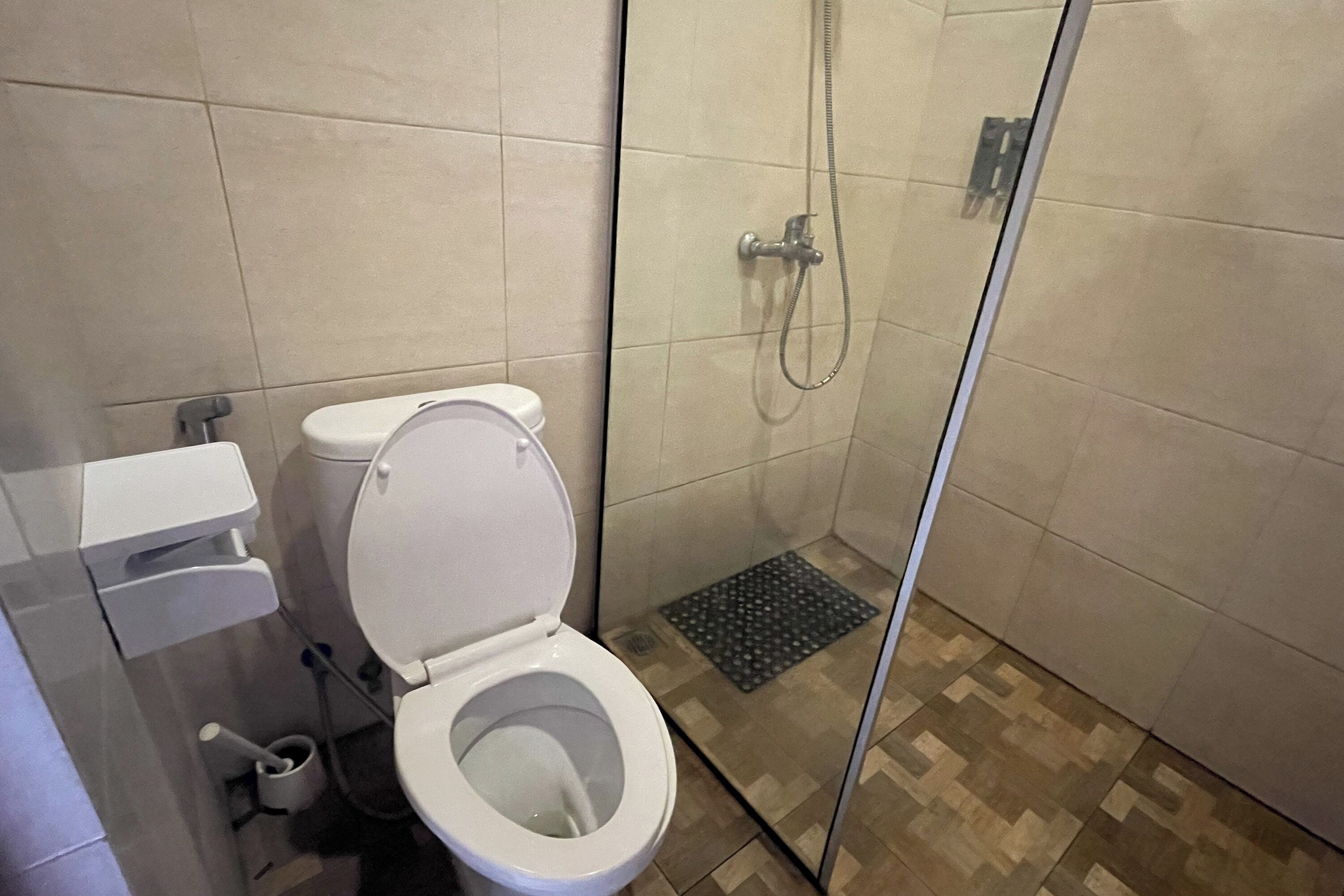 Um banheiro moderno com vaso sanitário, chuveiro e área de box envidraçada.