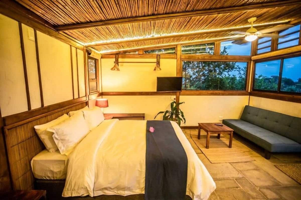 Um quarto com uma cama, um sofá, uma mesinha e uma televisão.