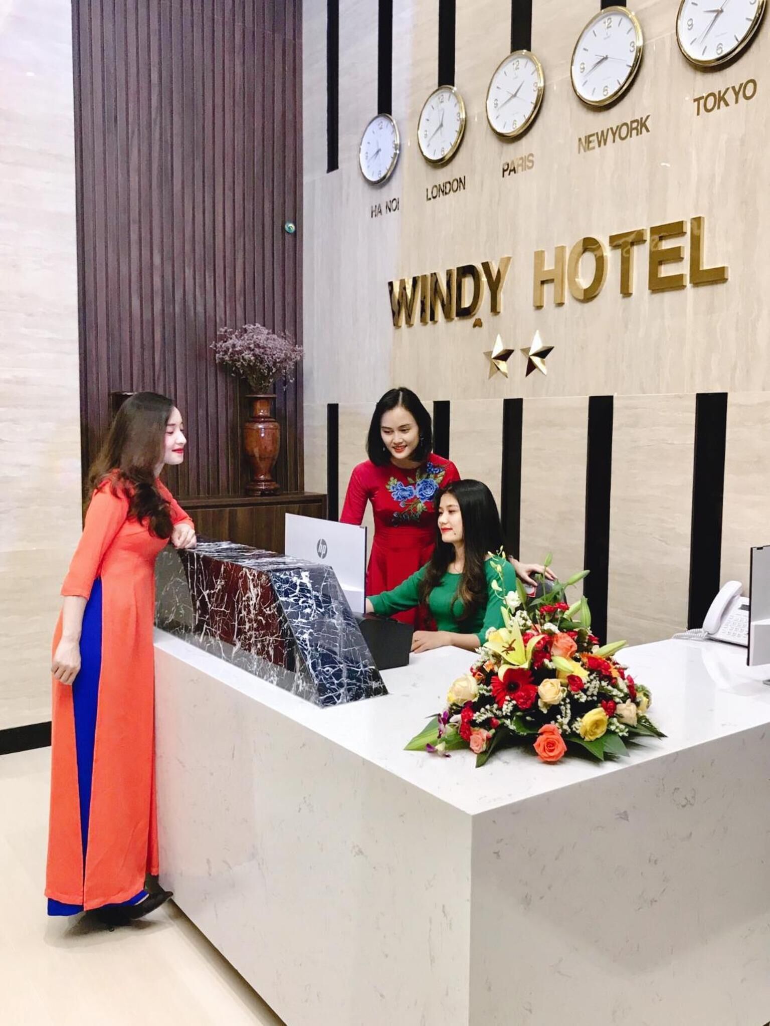 Bancada de recepção do Hotel Windy com relógios exibindo os horários de Londres, Paris, Nova York e Tóquio.