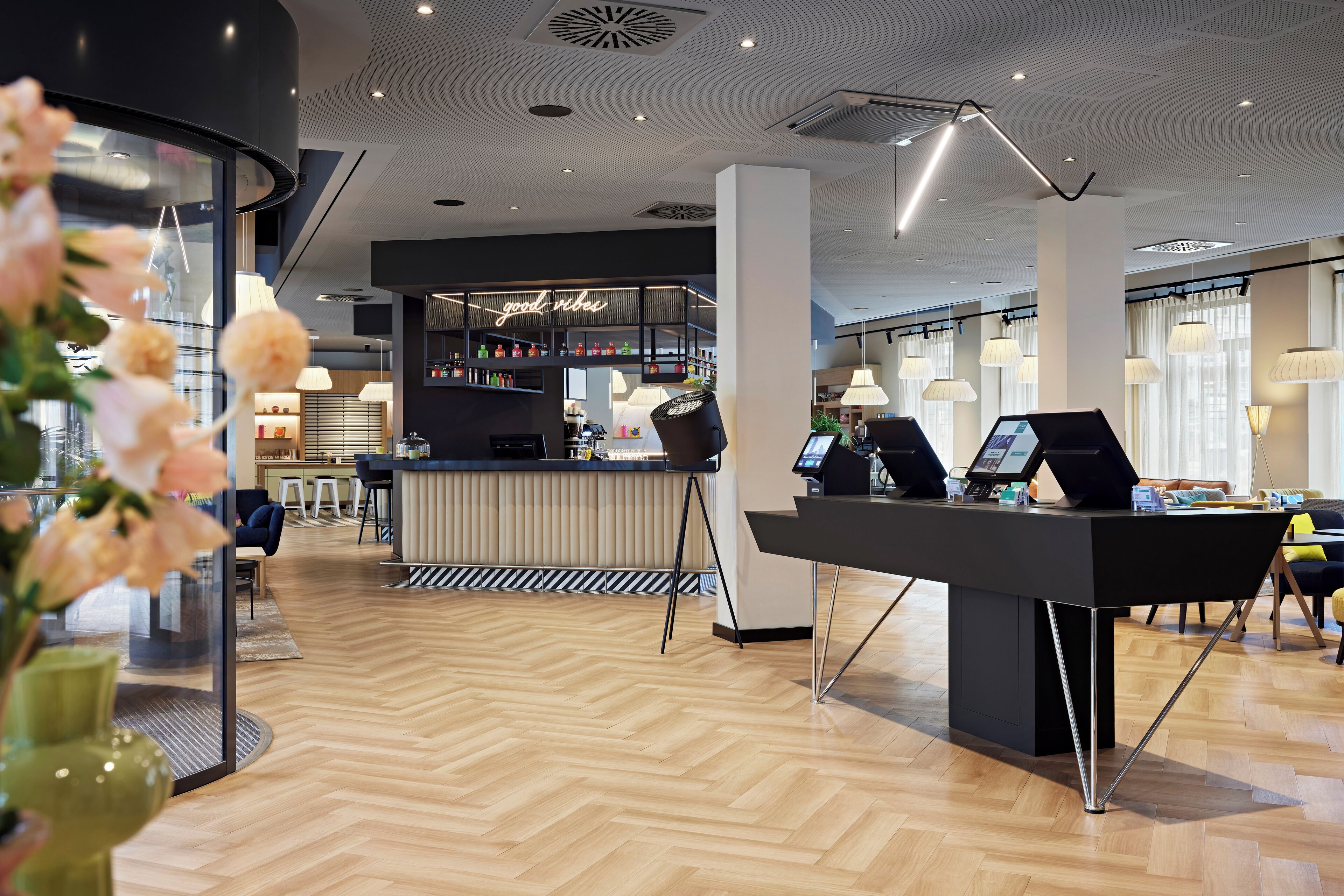 Decoração moderna com balcão de recepção, área de bar e espaço de estar com um letreiro que transmite uma atmosfera agradável.