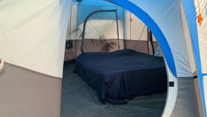 Uma tenda com uma cama, um saco de dormir e uma pequena mesa.