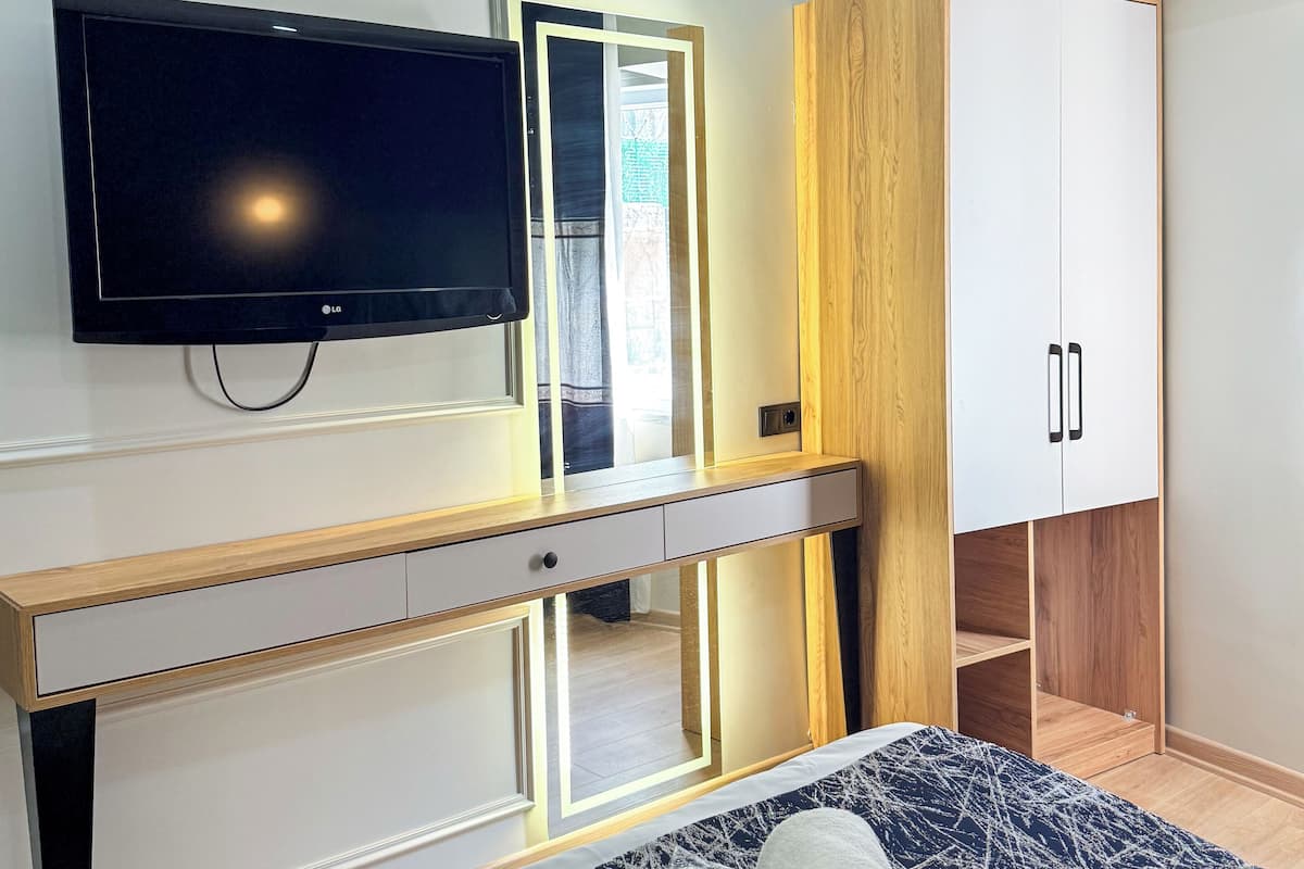Quarto de hotel moderno com cama, televisão, guarda-roupa e espelho.