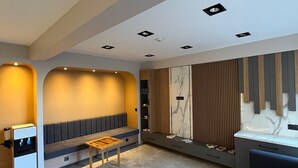 Uma área de lounge moderna com um banco, uma máquina de café e piso de mármore.