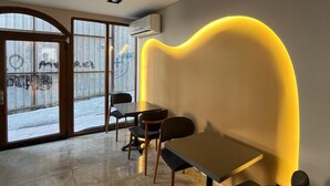 Um interior moderno com área de estar, mesas e cadeiras, uma janela ampla com vista e um aparelho de ar condicionado na parede.