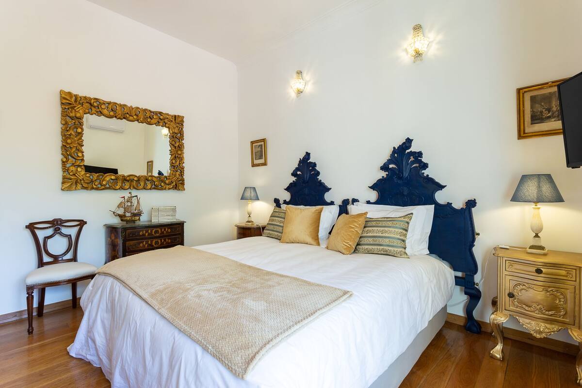 Quarto bem arrumado com uma cama grande, cômoda, cadeira e mesa de cabeceira com luminárias.