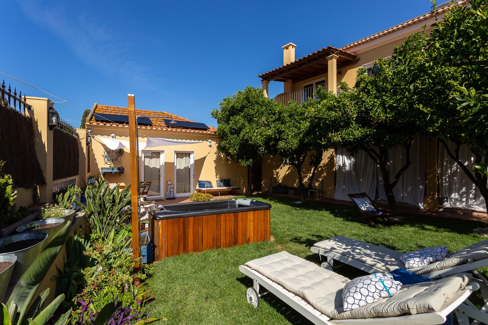 Um quintal com hidromassagem, cadeiras de descanso e um espaço de varanda com pérgola.