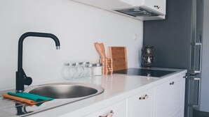 Uma cozinha moderna com pia de aço inoxidável, torneira preta e bancada branca.