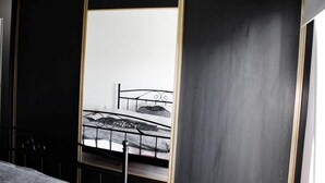 Quarto com uma cama, uma janela e vista parcial de um guarda-roupa.