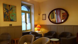 Um quarto acolhedor com uma janela grande, um espelho redondo e vários poltronas.