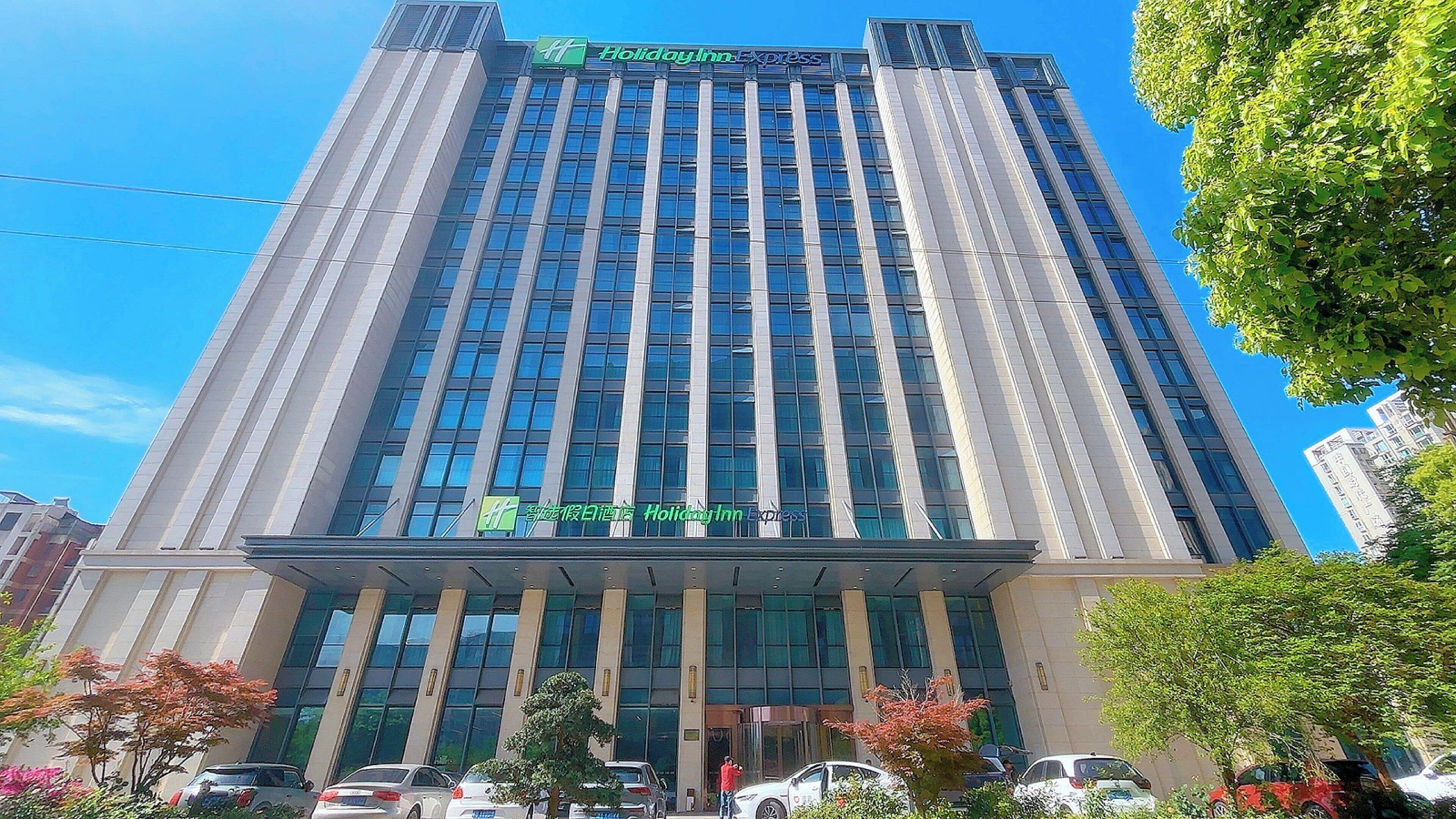Um edifício alto de hotel com fachada moderna em vidro e um letreiro chamativo 'Holiday Inn Express' no topo.