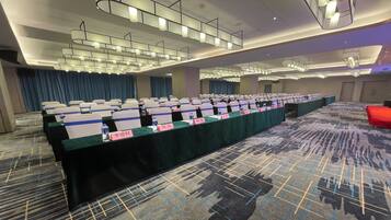 Sala de conferências com fileiras de cadeiras, placas de identificação e mesas com garrafas de água.