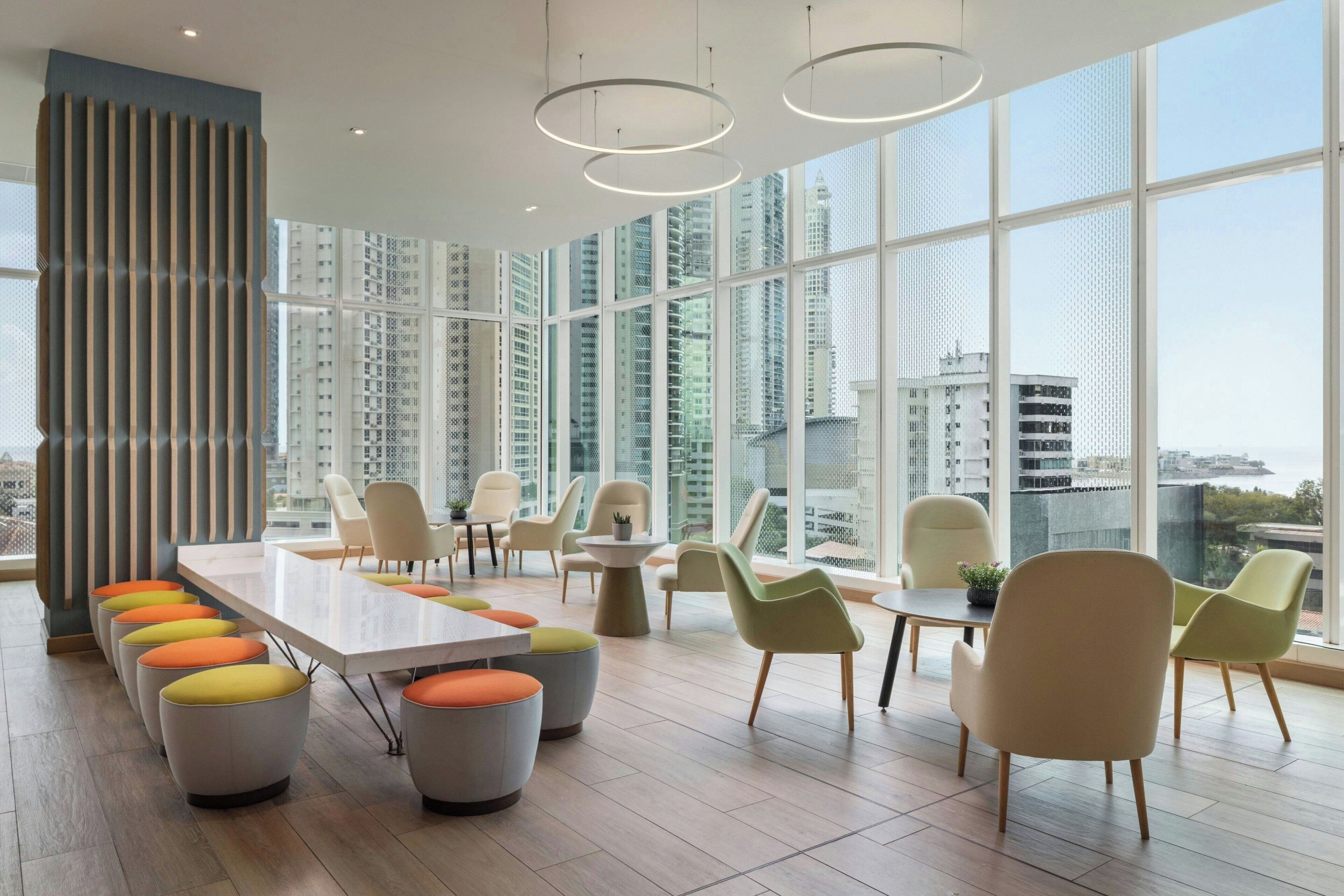 Espaço de escritório moderno com uma mesa comprida, várias cadeiras e grandes janelas com vista para a cidade.