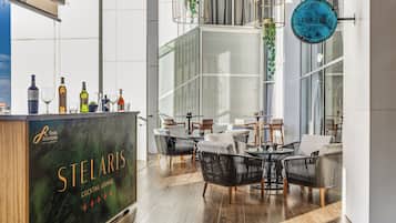 Um lounge de cocktails moderno com balcão, cadeiras de vime e uma parede de vidro.