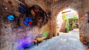 Um interior rústico com parede de pedra, um banco de madeira e uma placa indicando um hotel.