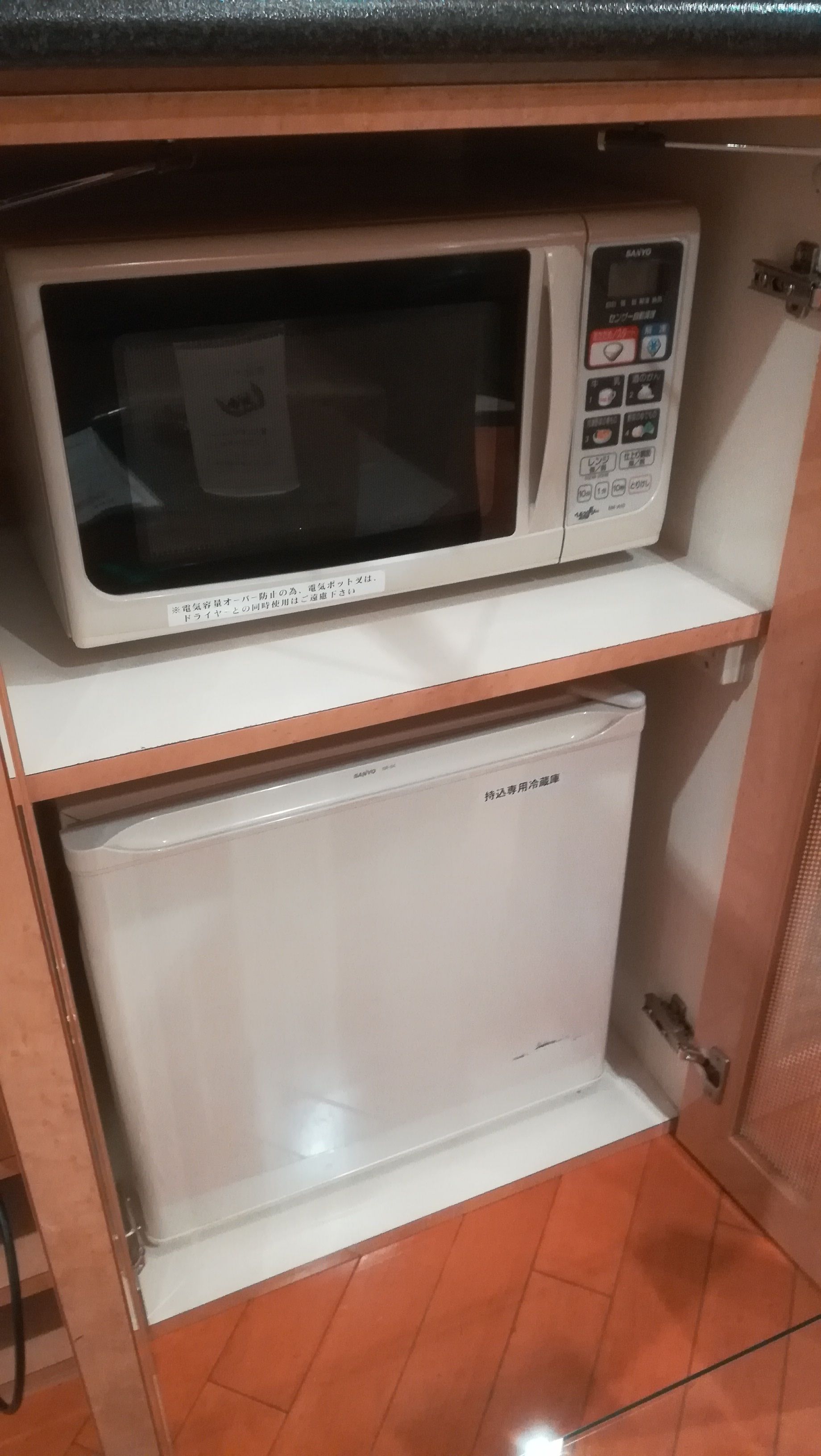 Um micro-ondas e uma geladeira em um armário de cozinha.