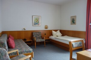 Quarto de hotel pequeno com uma cama, um sofá, uma cadeira e uma mesa.