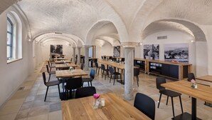 Uma ampla sala de jantar com tetos altos e abobadados e várias mesas e cadeiras.