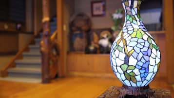 Um vaso de vitrais sobre uma mesa de madeira num quarto com escada e corrimão de madeira.