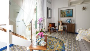 Quarto com escrivaninha de madeira, uma cadeira, um espelho grande e um quadro na parede.