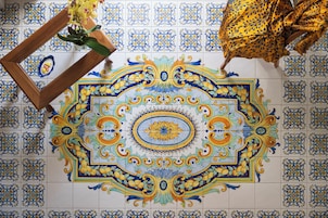 Piso de azulejos com um desenho central grande e ornamentado, rodeado por azulejos menores com padrões.