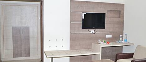 Uma sala de estar moderna com uma TV de tela plana presa à parede, uma mesinha, um sofá e uma porta.