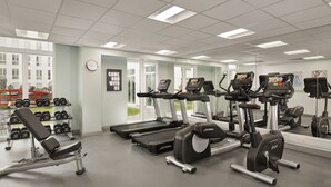 Uma academia com esteiras, elípticos e equipamentos de musculação.