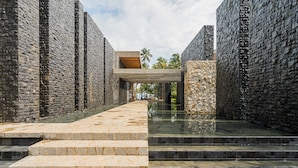 Um caminho de pedras leva a uma área de piscina com uma estrutura moderna no centro.
