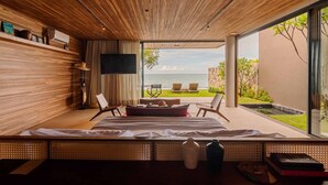 Quarto moderno com uma cama grande, uma televisão e vista para o mar.