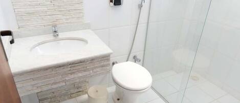 Uma casa de banho com lavatório branco, sanita e cabine de duche em vidro.