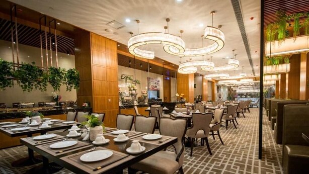 Restaurante com várias mesas postas para atendimento, piso estampado e luminárias modernas.