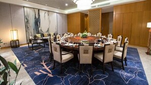 Uma sala de conferência com uma mesa redonda, cadeiras e um candelabro.