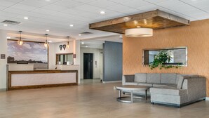 Um hall amplo com balcão de atendimento, um sofá cinza e uma planta pendente.