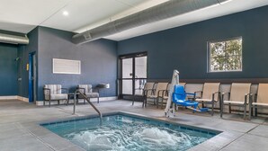 Uma área de piscina com hidromassagem, assentos e vista para o exterior.