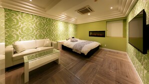Quarto com cama, mesinha de centro de vidro, sofá branco e parede com padrão verde.